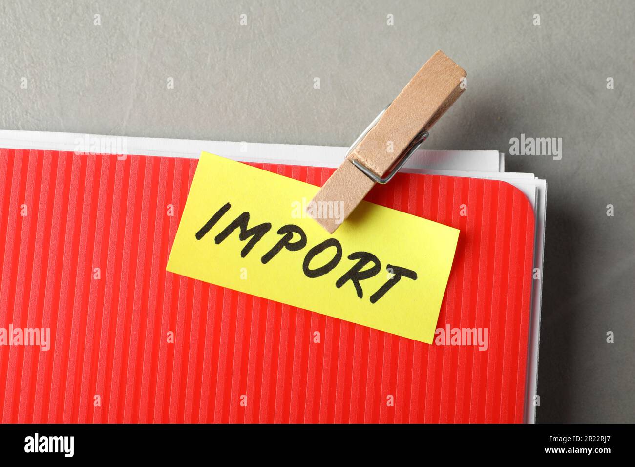 Note with word Import attached to folder of documents on grey table ...