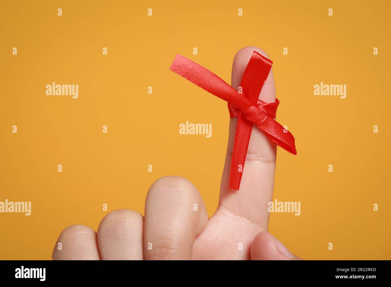 Man showing index finger with red tied bow as reminder on orange ...