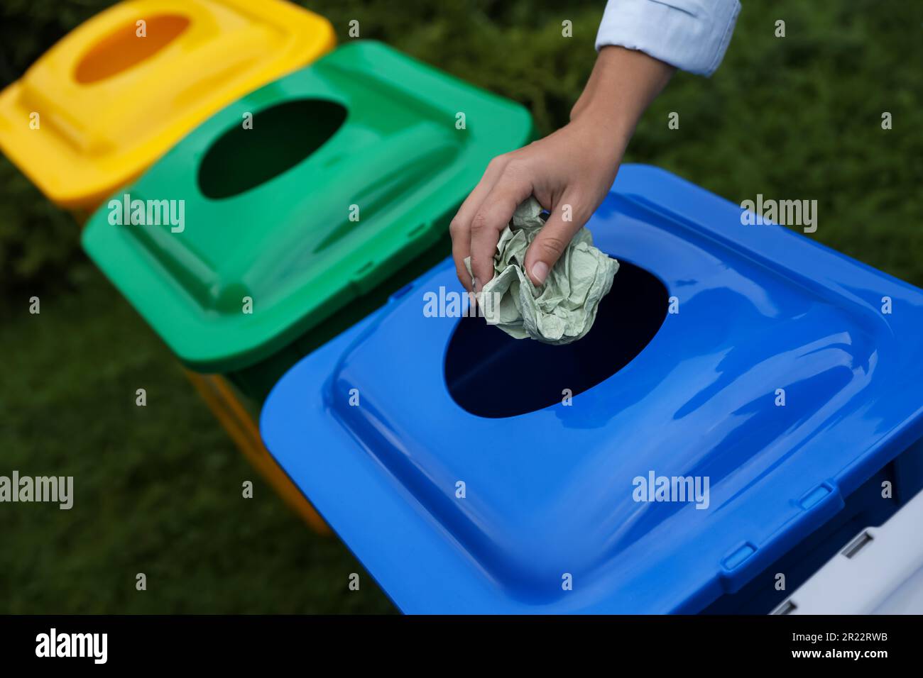 Woman throwing crumpled tissue into recycling bin outdoors, closeup ...
