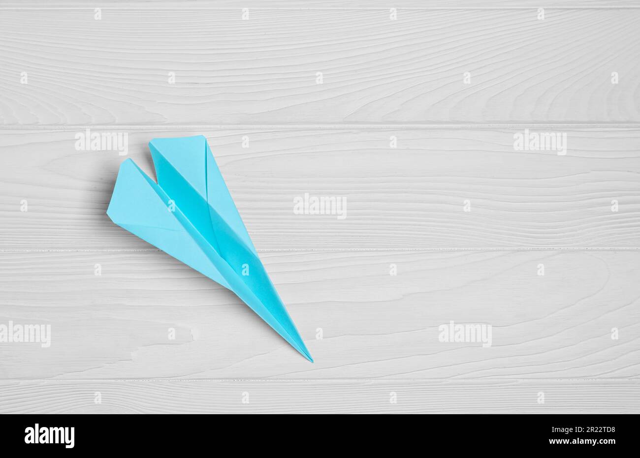 Handmade paper plane on white wooden table, top view. Space for text ...