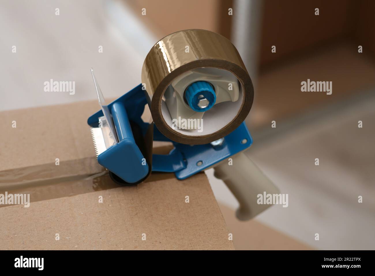 Taping cardboard box with adhesive tape dispenser indoors Stock Photo ...
