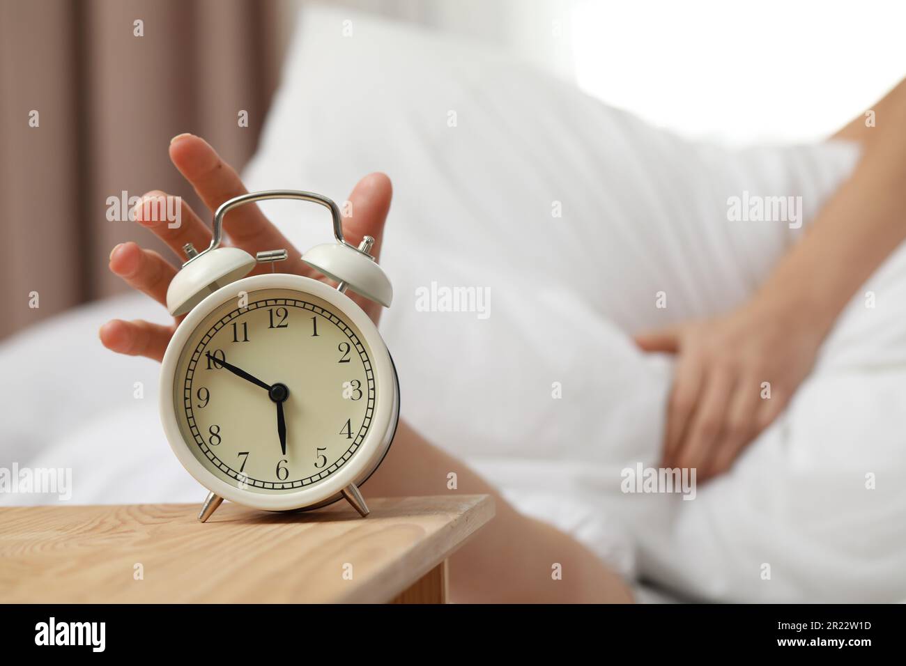 Woman turning off alarm clock in bedroom, closeup. Space for text Stock ...