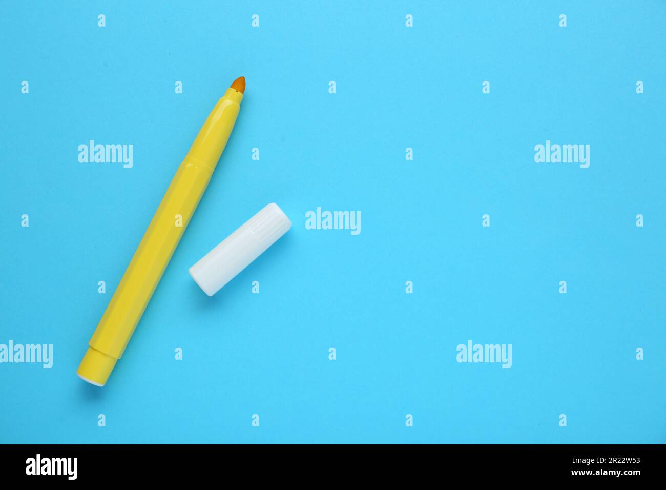 Bright yellow marker and cap on light blue background, flat lay. Space ...