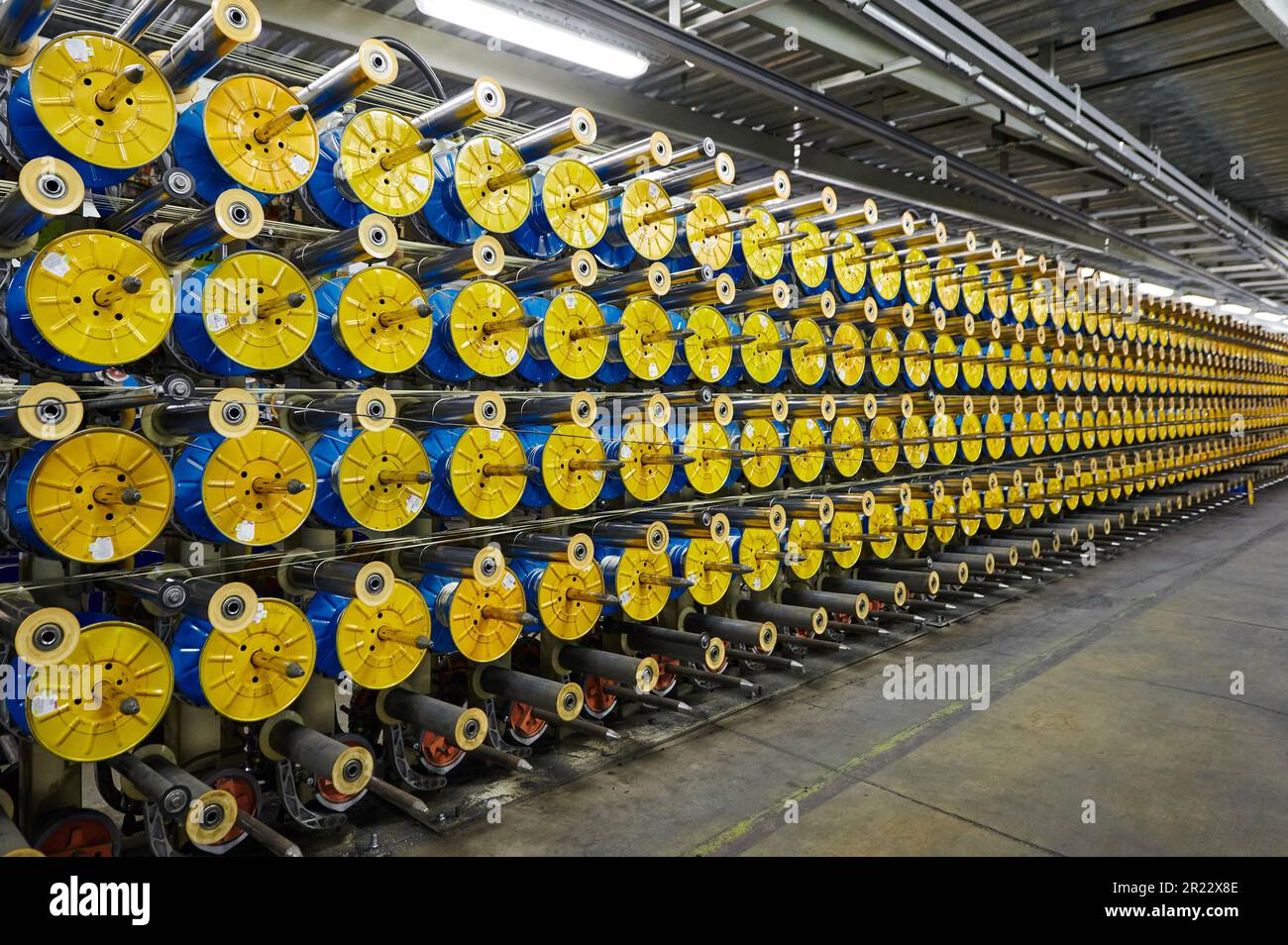 Bright yellow spools on shiny metal rods in plant workshop Stock Photo ...