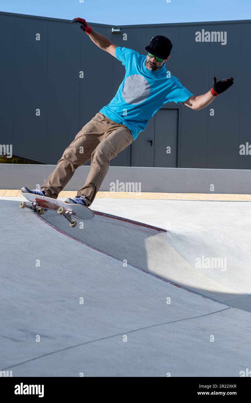 Skateboarder doing frontside five-o grind trick in concrete skatepark ...