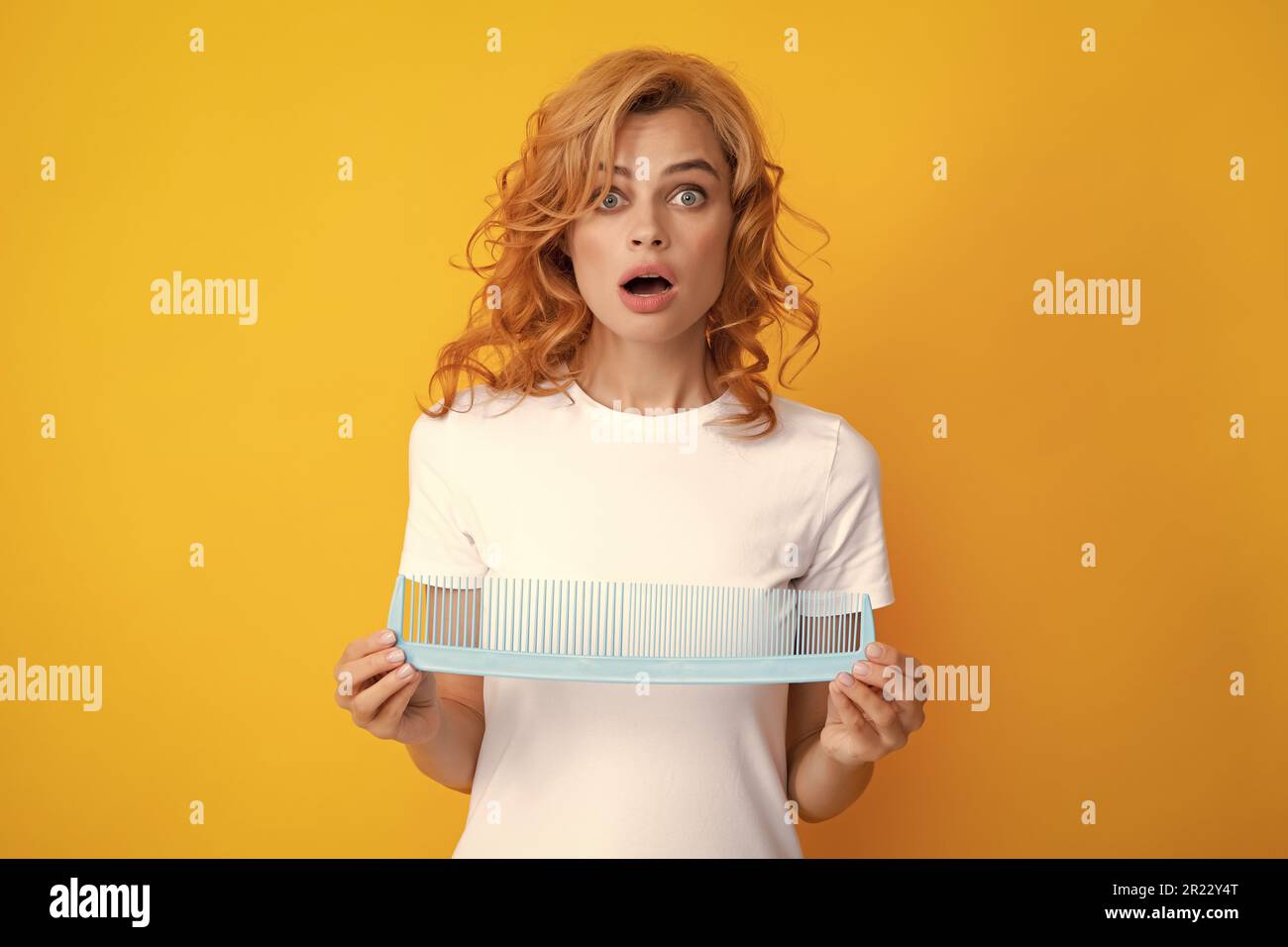 Funny girl combing hair. Redhead woman with a comb, isolated on yellow ...