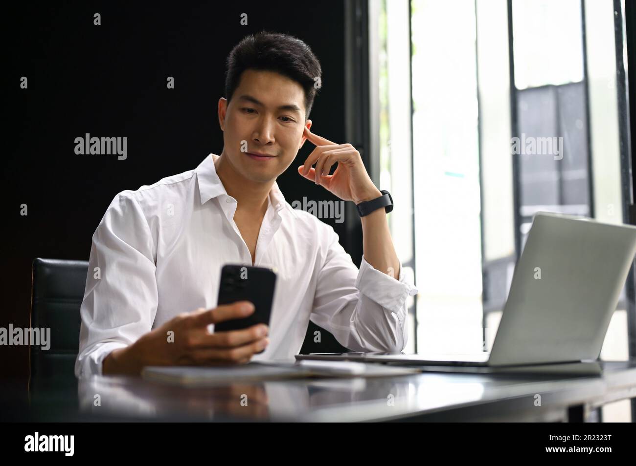 Happy and handsome millennial Asian businessman checking messages on ... Happy and handsome millennial Asian businessman checking messages on ...