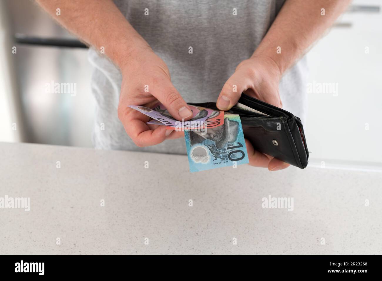 Male hands taking Australian bank notes from a worn black wallet ...