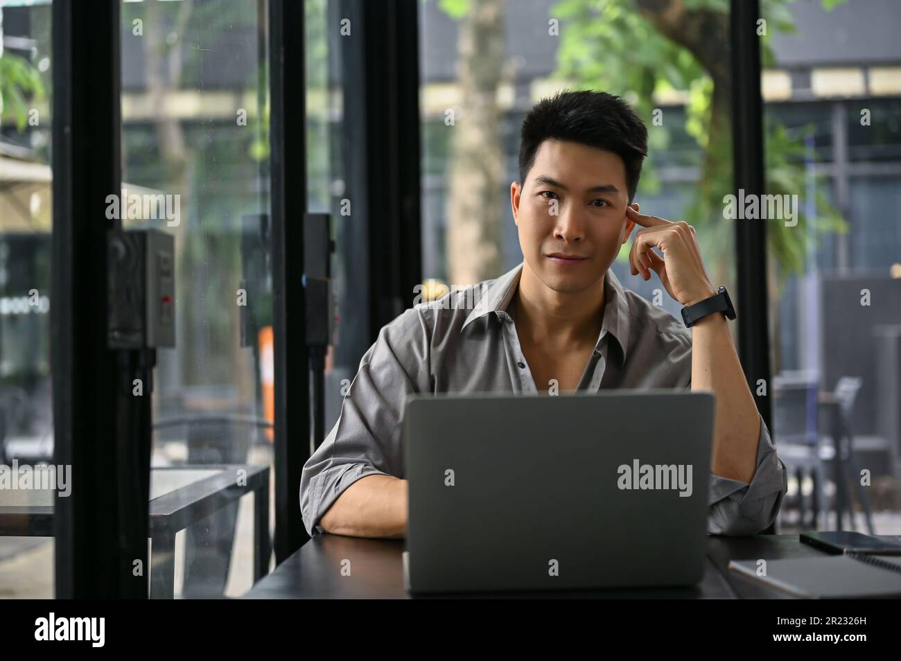Portrait of a smart and handsome millennial Asian businessman sits in a ...