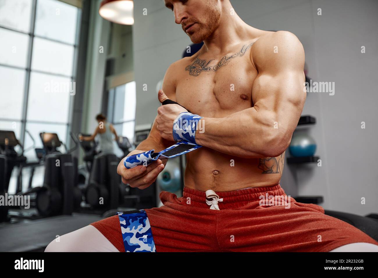 Young sporty handsome man wraps his arms with gymnastic bandage getting ...