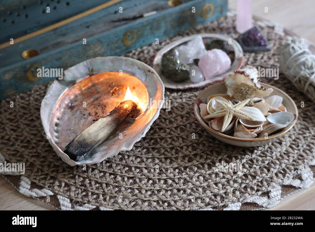 A knitted rug with bowls with shells and stones and a burning wooden ...