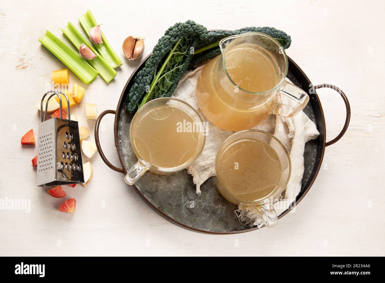 Two cups and glass mug of homemade chicken bone broth on white ...