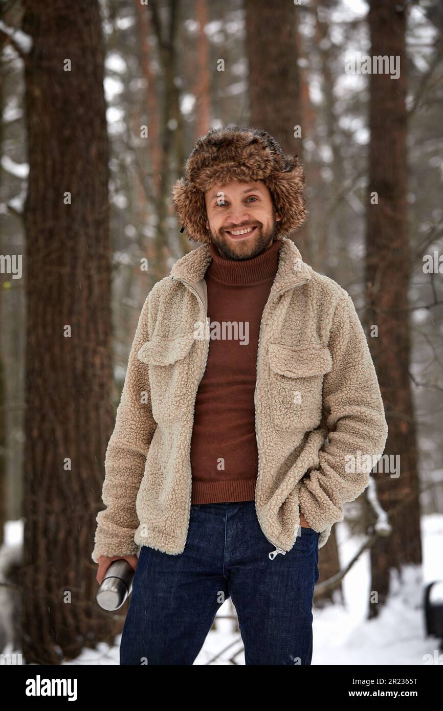 Smiling handsome man in worm hat is enjoying cold snowy weather in ...