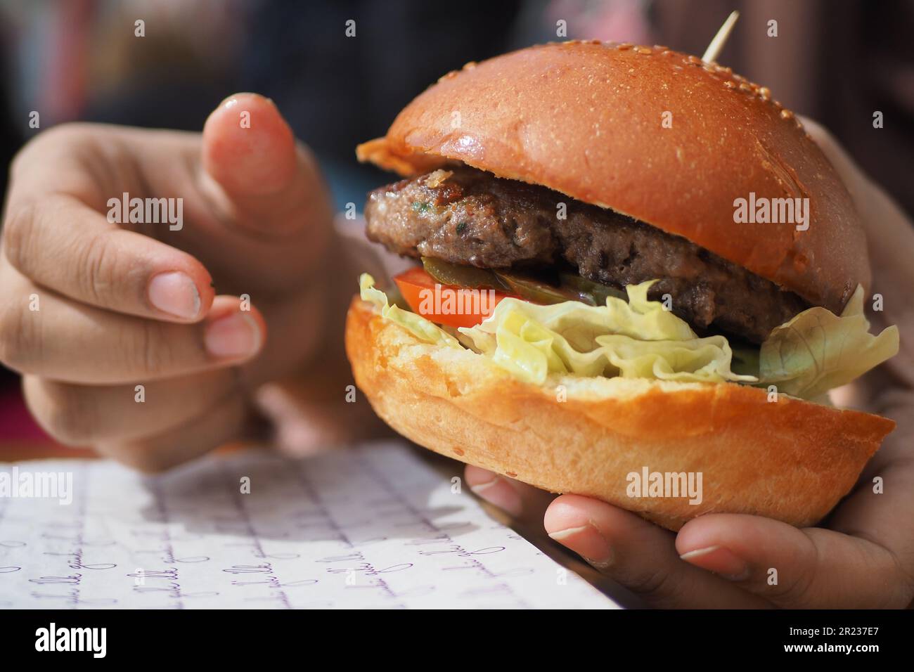 hand holding beef burger on table close up Stock Photo - Alamy