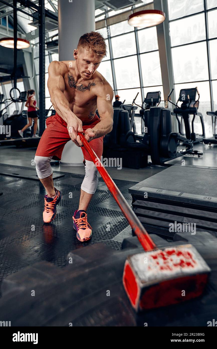 Strength concept. Male athlete using hammer during fitness workout ...
