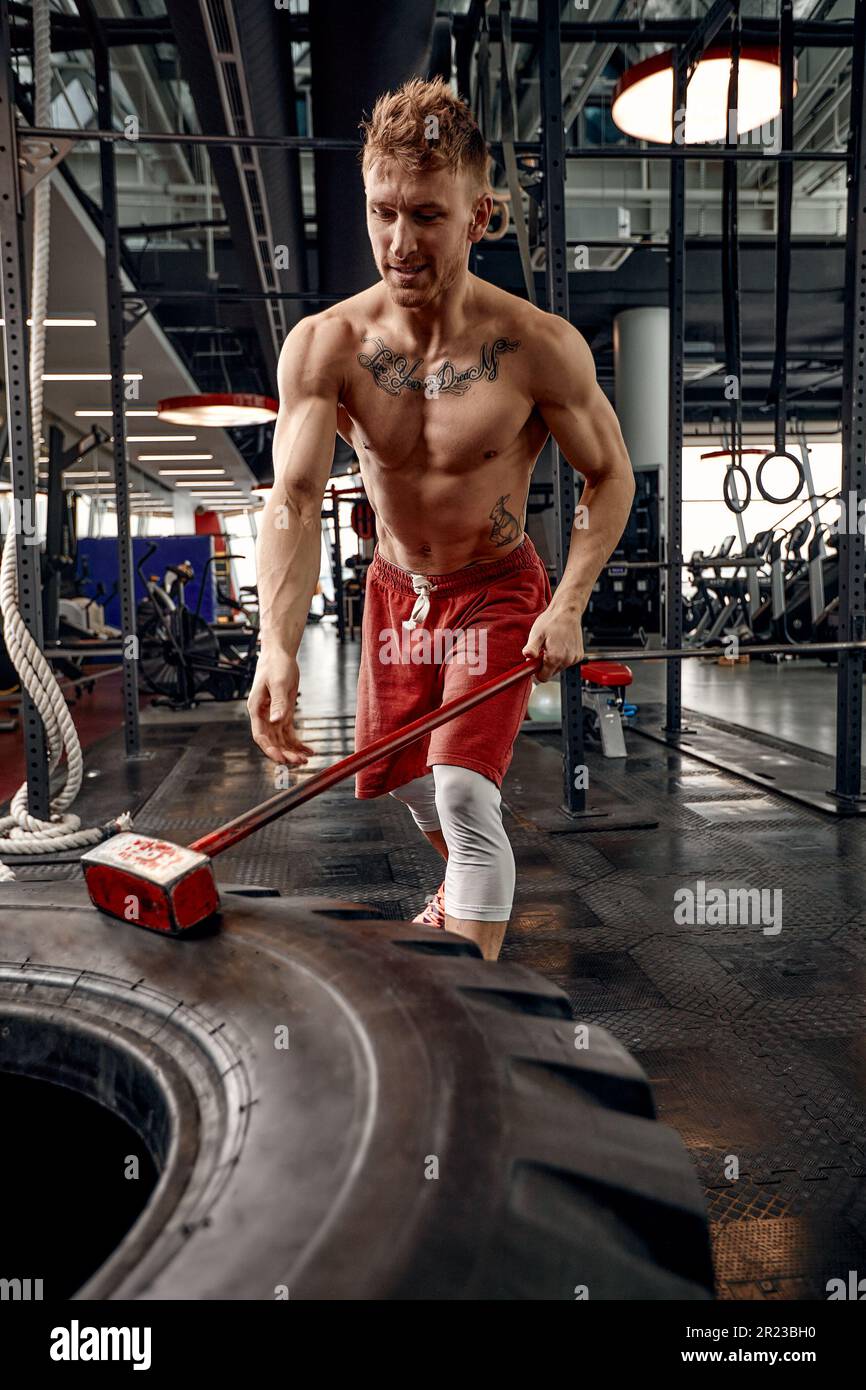 Strength concept. Male athlete using hammer during fitness workout ...