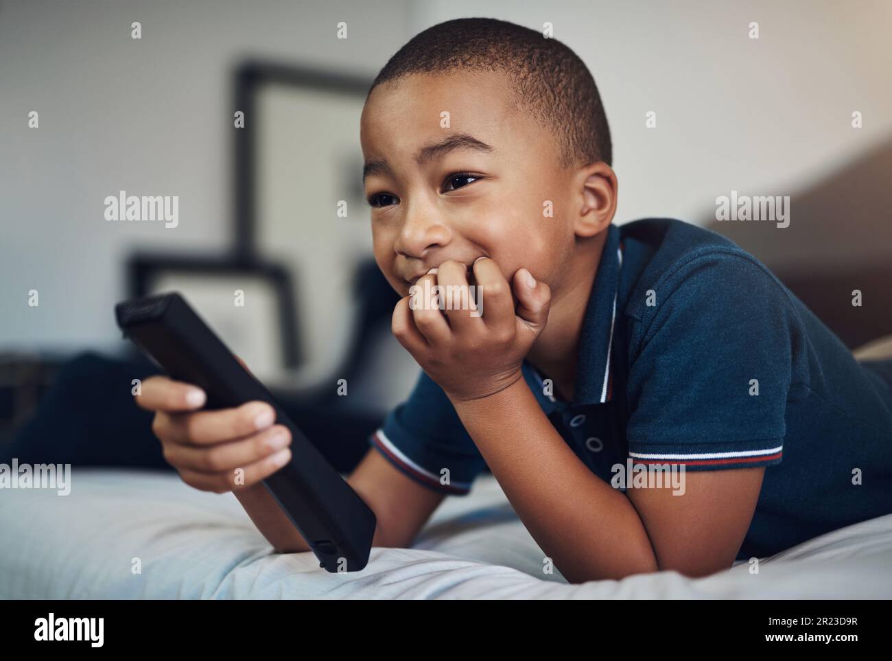 Its time for my favourite show. a young boy using a remote control ...