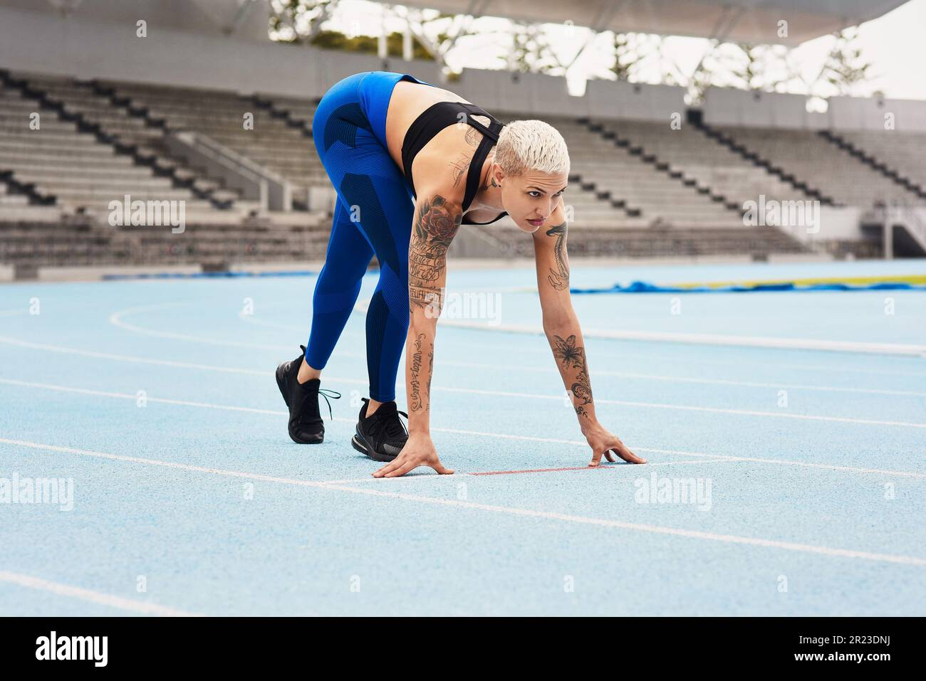 Taking up the position. Full length shot of an attractive young female athlete standing in the ...