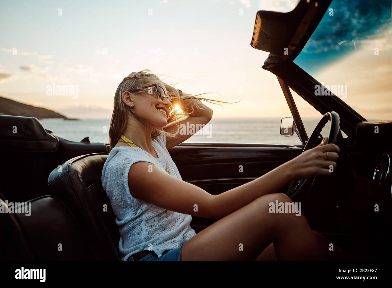 Rounding off the road trip with a beautiful sunset. a happy young woman ...