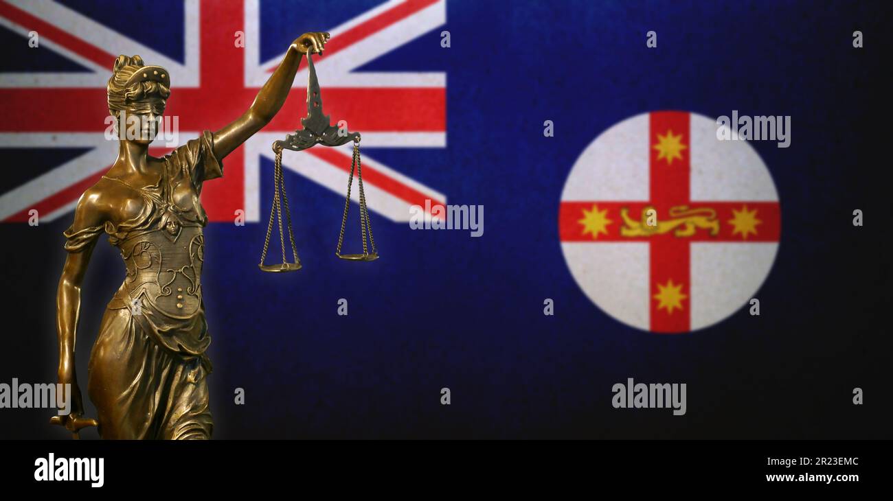 Close-up of a small bronze statuette of Lady Justice before a flag of ...