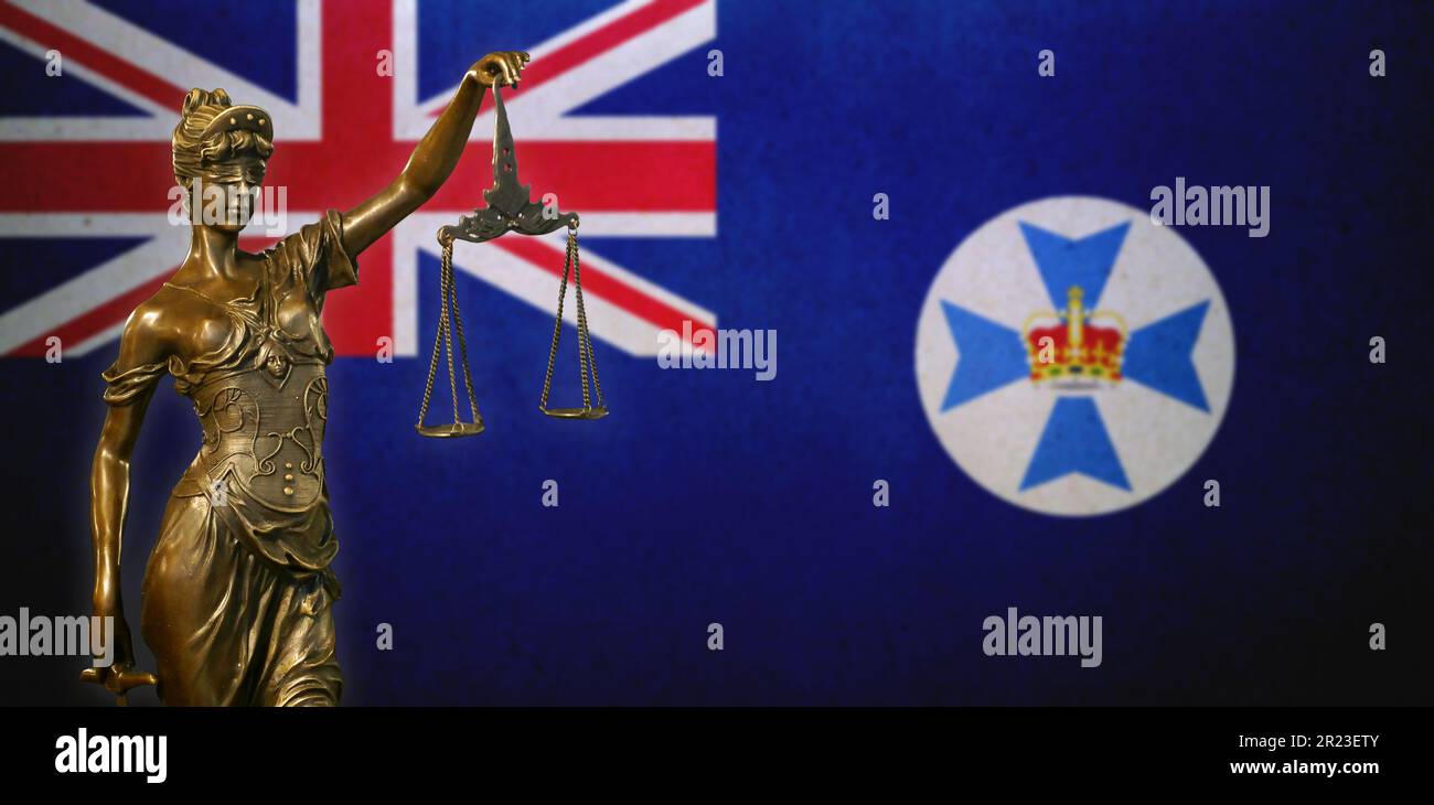 Close-up of a small bronze statuette of Lady Justice before a flag of ...