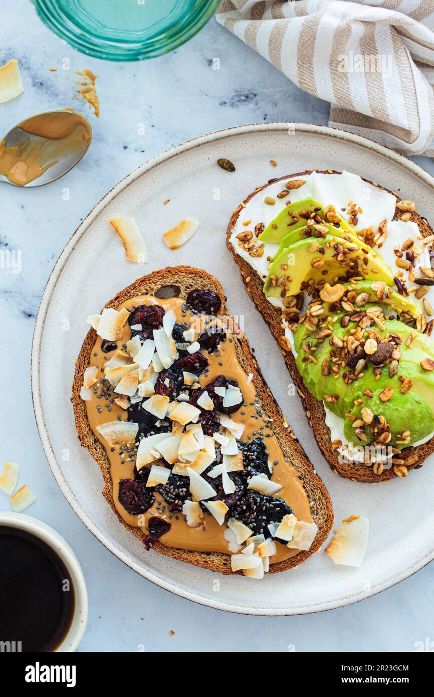 Vegan breakfast toasts with avocado and peanut butter on a white marble ...