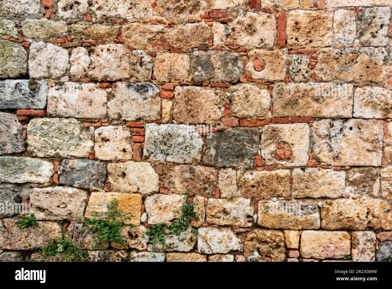 Detail of medieval stone wall, with gaps filled with red brick material ...