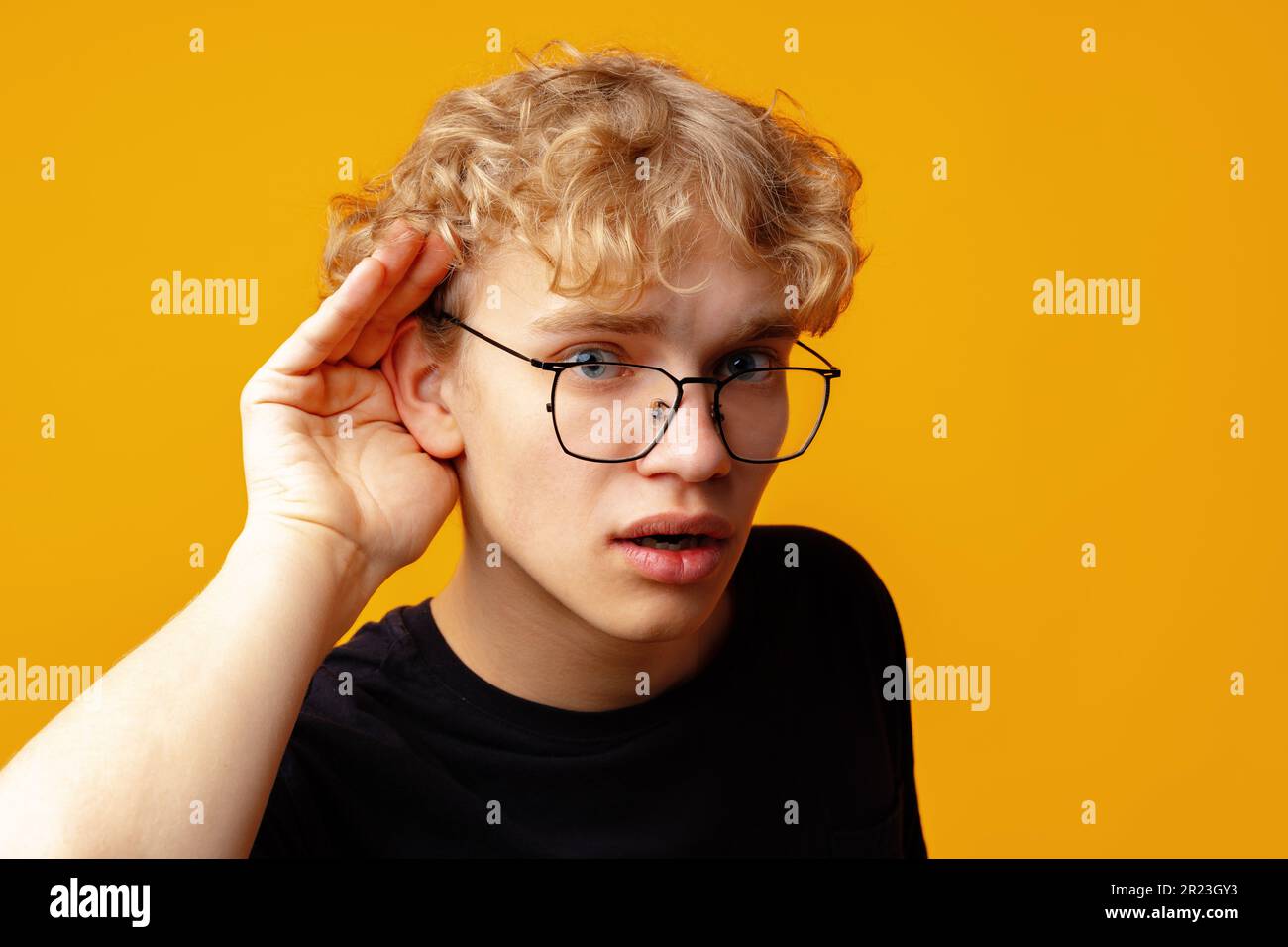 Young handsome man standing over yellow background with hand over ear ...