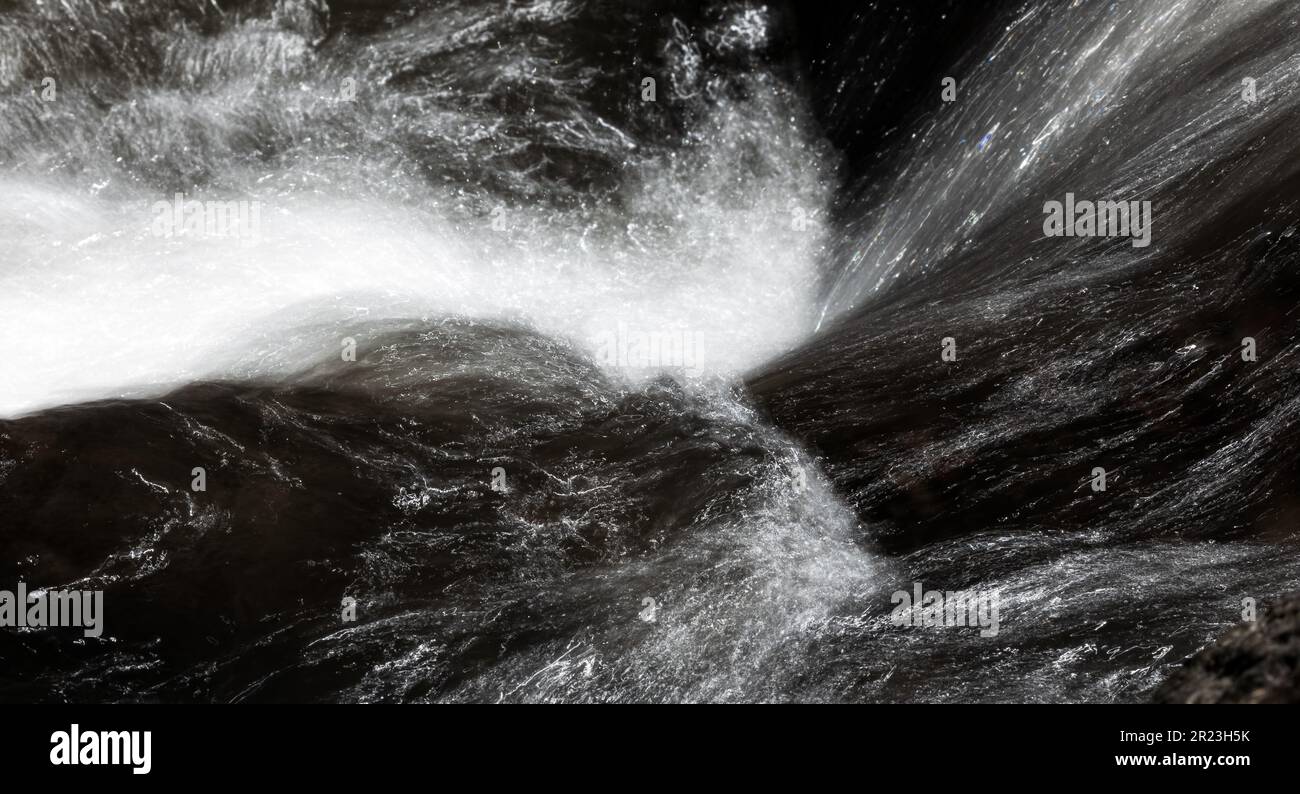 Long exposure of flowing water in natural stream with dark background ...