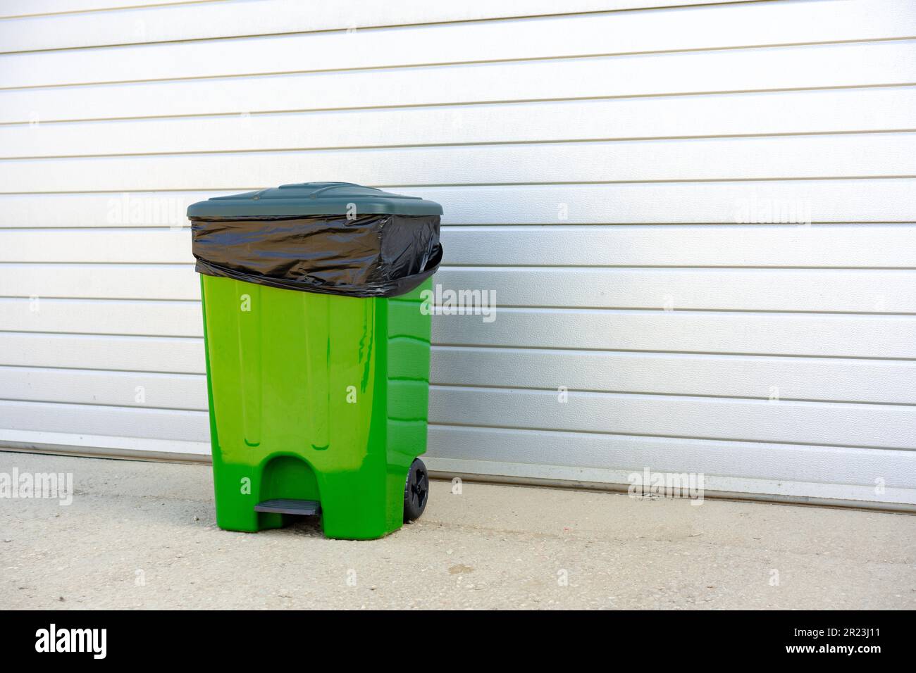 Green plastic garbage container standing in the street Stock Photo - Alamy