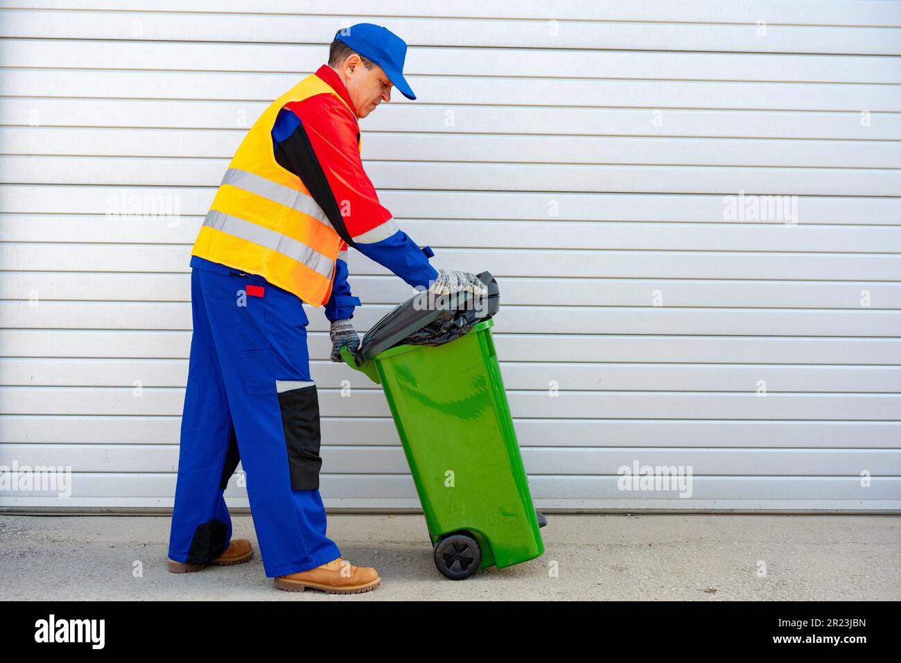 Janitor takes garbage out of trash container outdoors Stock Photo - Alamy