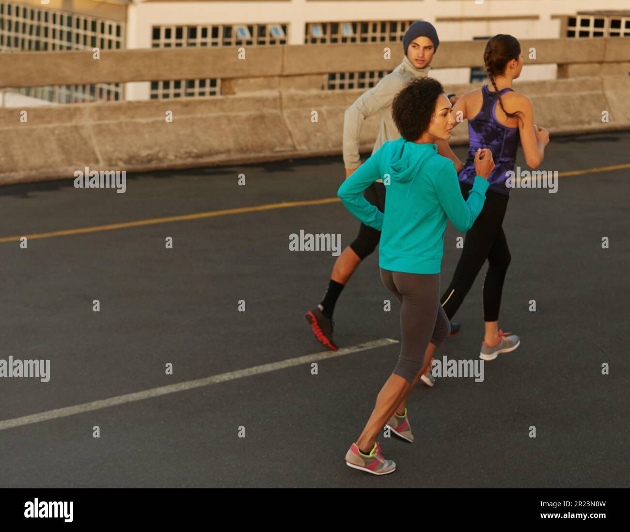 Taking in a morning run. three young joggers running down an empty ...
