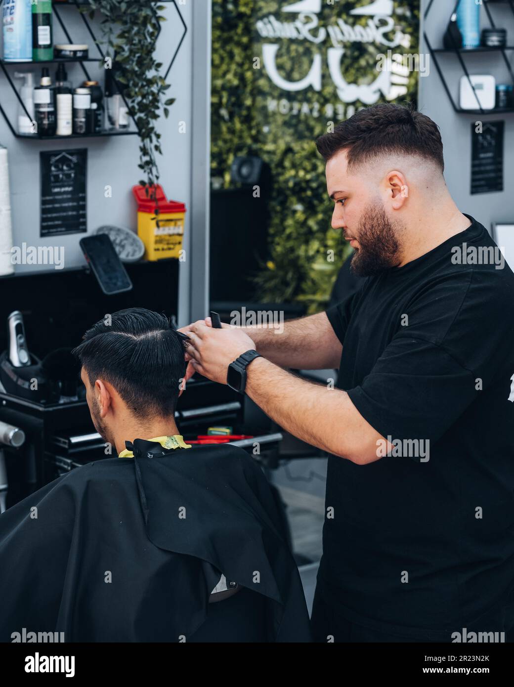 A vertical of a barber trimming a male customer's hair in a salon Stock ...
