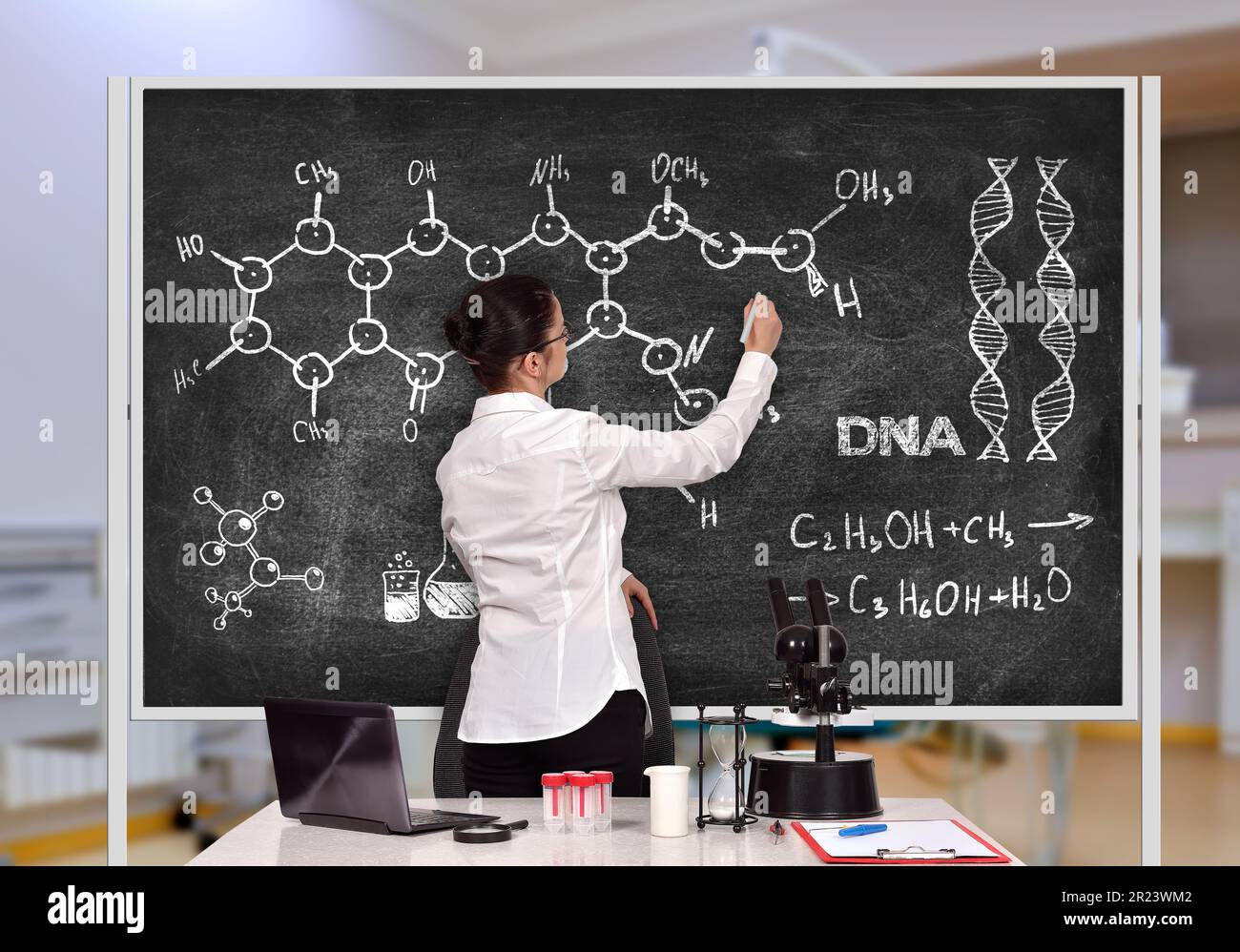female scientific researcher drawing chemical scheme on blackboard in ...