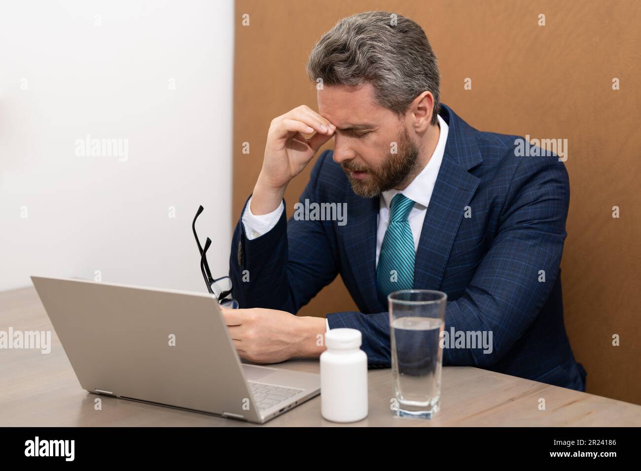 Headache and eye strain on laptop. Business man with stress and fatigue eyestrain. Businessman ...