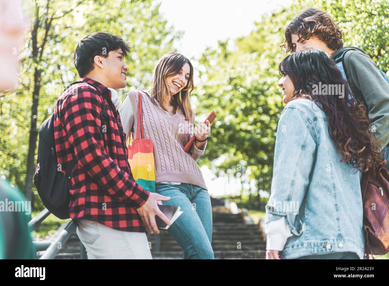 Four Caucasian students with backpacks, notebooks, and tablets ...
