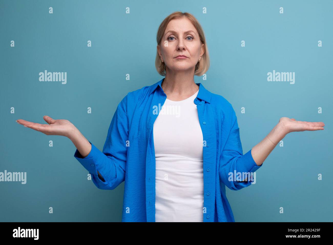 surprised blond mature woman in disbelief on blue background with ...