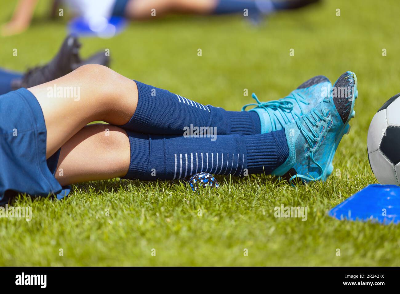 Young boy rolling calf using foam roller at training pitch. School ...