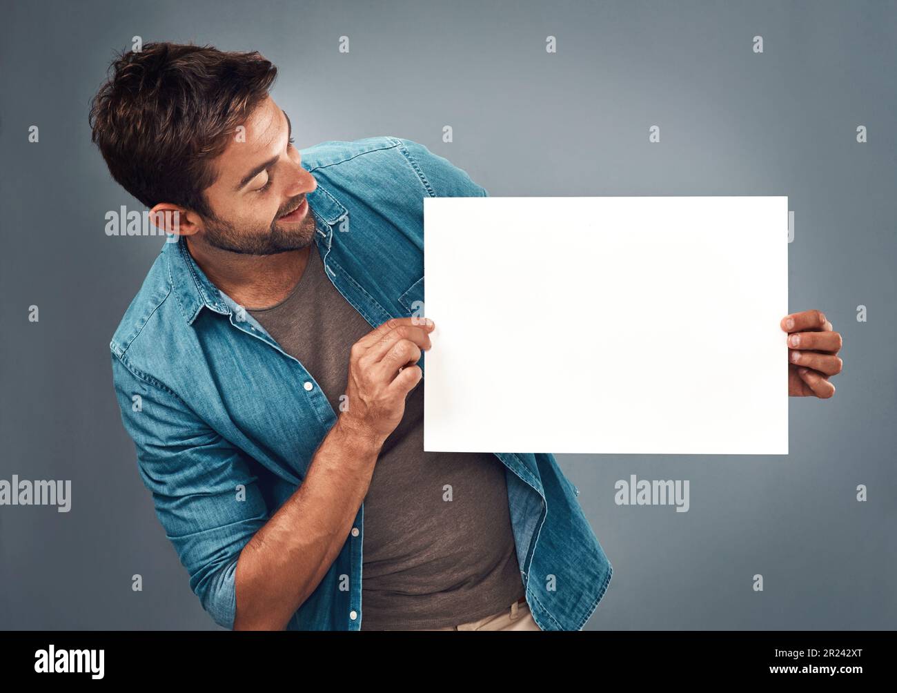 Man, billboard sign and mockup for marketing, advertising or branding against a grey studio ...