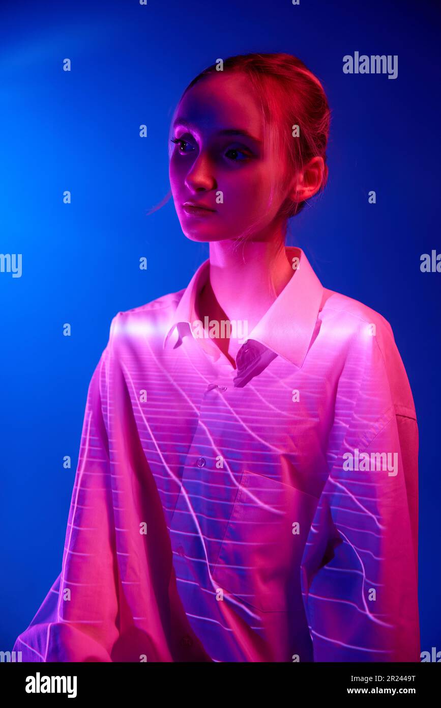 Power. Portrait of young girl in white blouse with neon filter ...