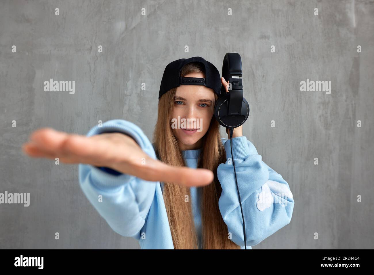 A young pretty long-haired DJ girl in a blue sweater and a black ...