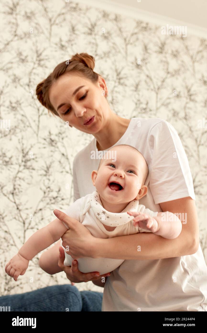 Loving mom carying her little baby at home. Bright portrait of happy mom holding her infant ...