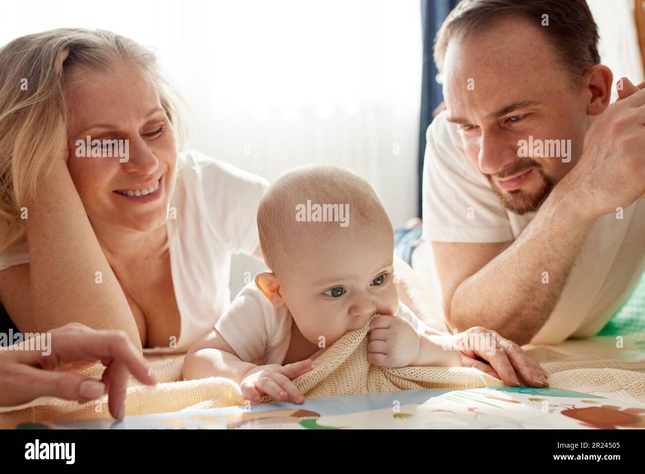 Loving grandma and dad hug and kiss their baby on the floor in the ...