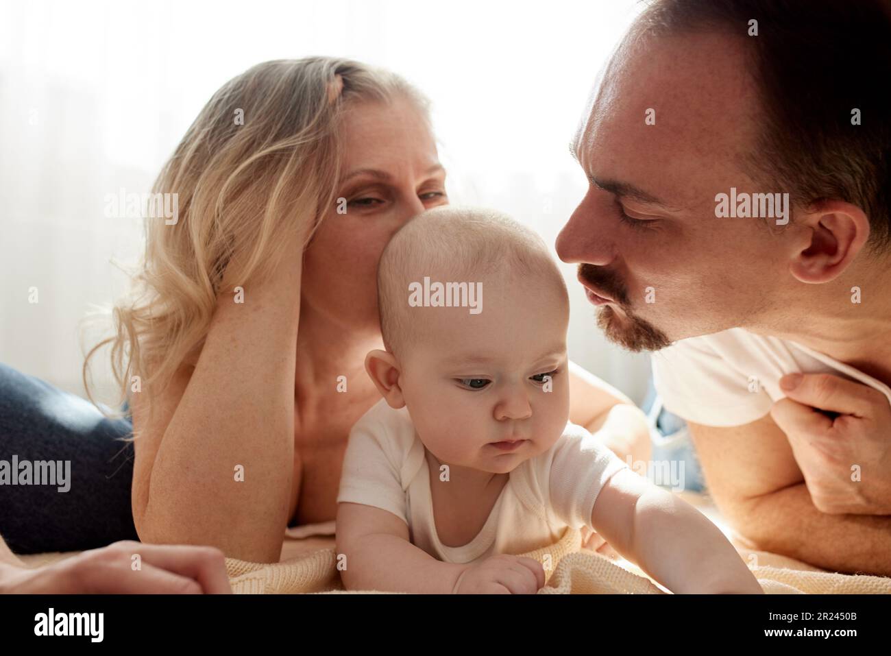 Loving grandma and dad hug and kiss their baby on the floor in the ...