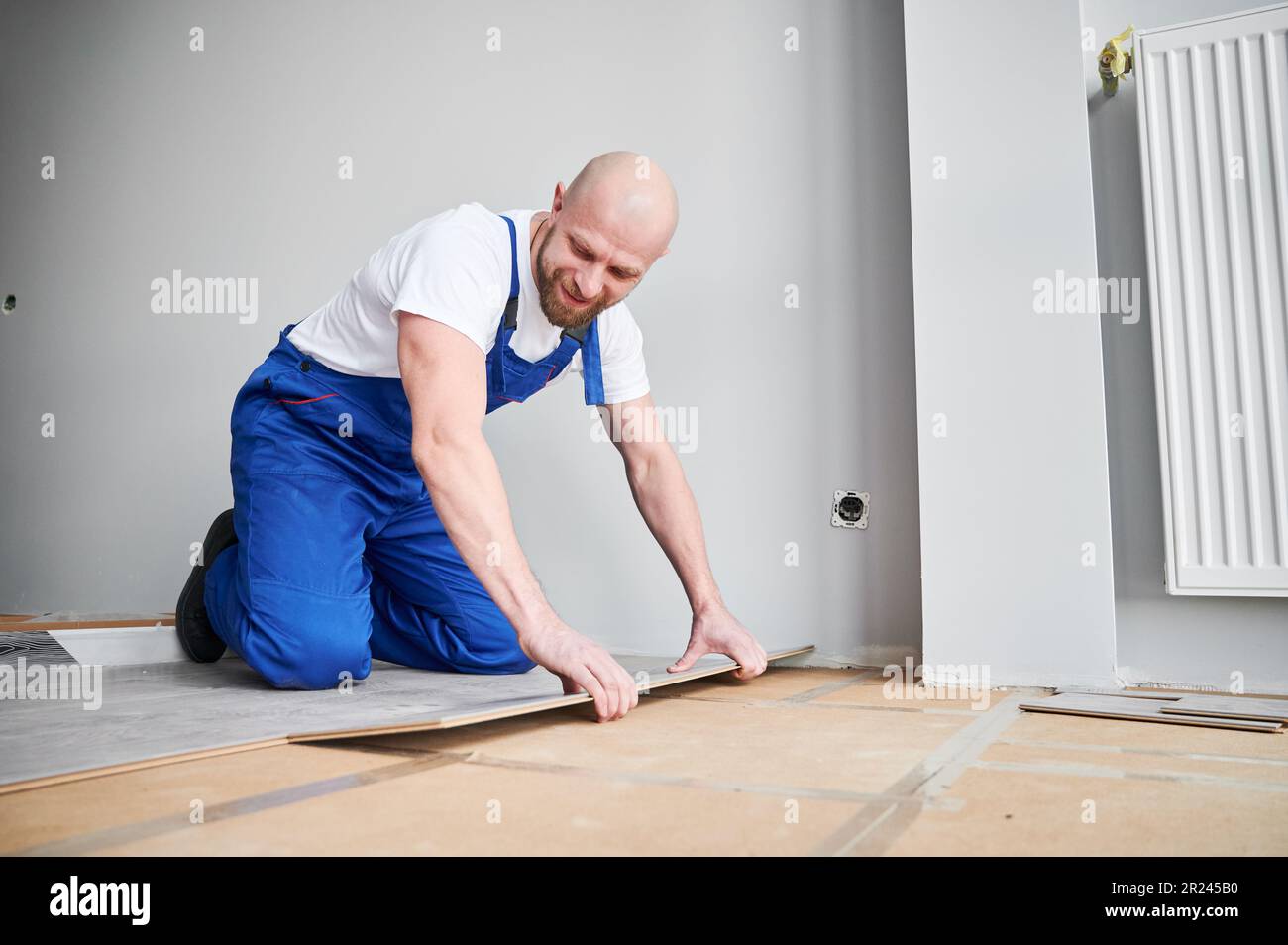 Male construction worker laying laminate wooden plank on floor ...