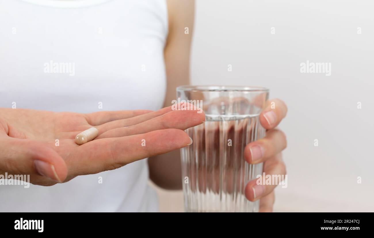 Female Holds Two Pills, Capsules OF Slippery Elm And Glass OF Liquid ...