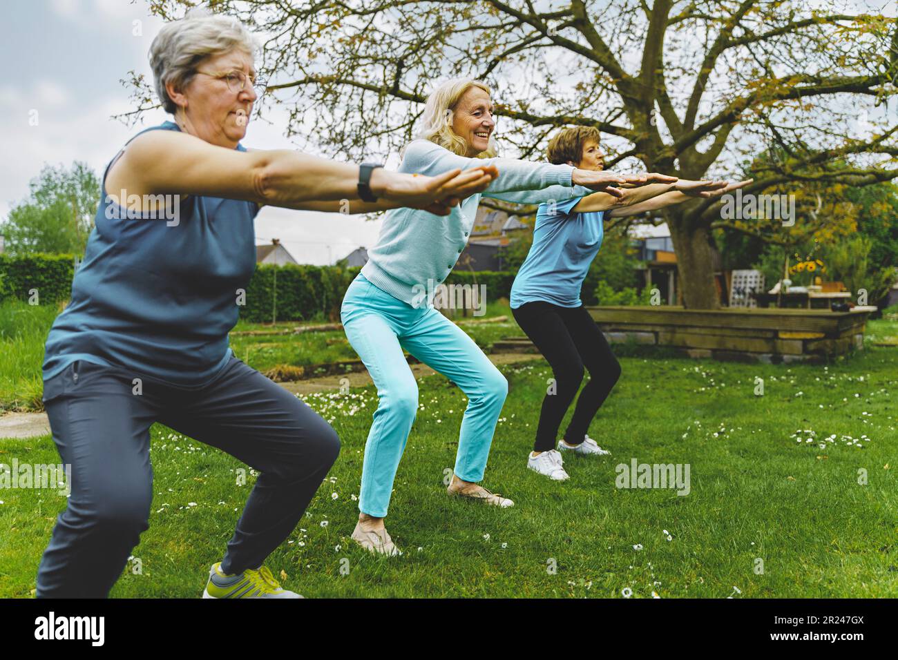 Three senior women performing squat exercises outdoors in a country ...