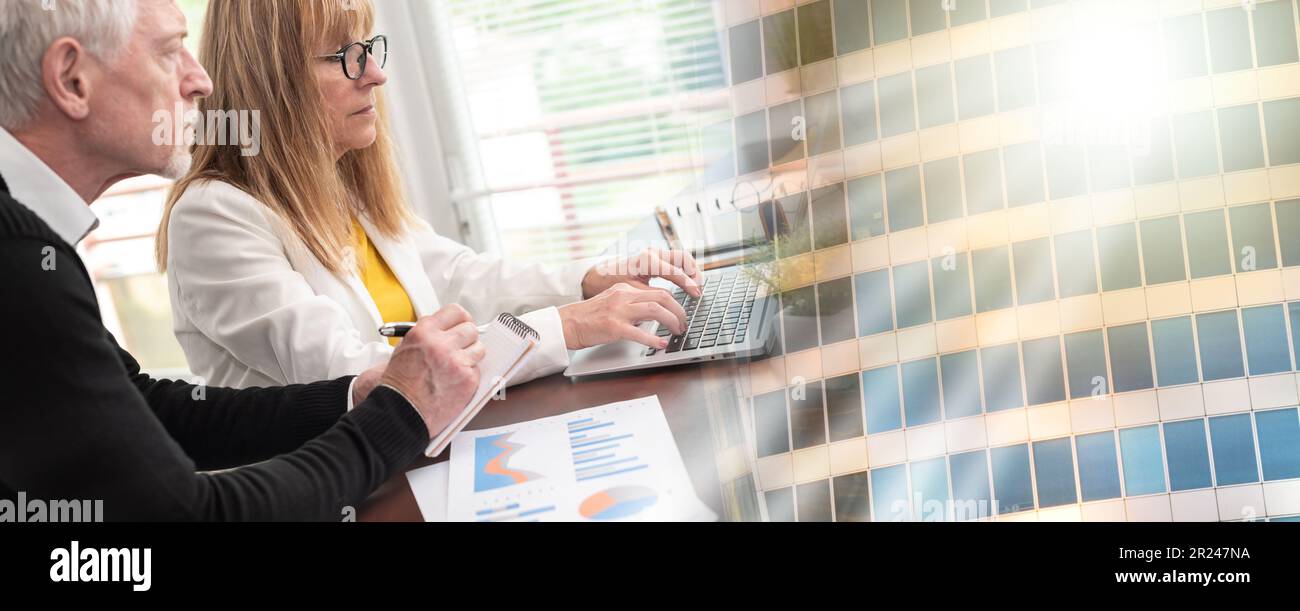 Two mature business people working together in office; multiple ...