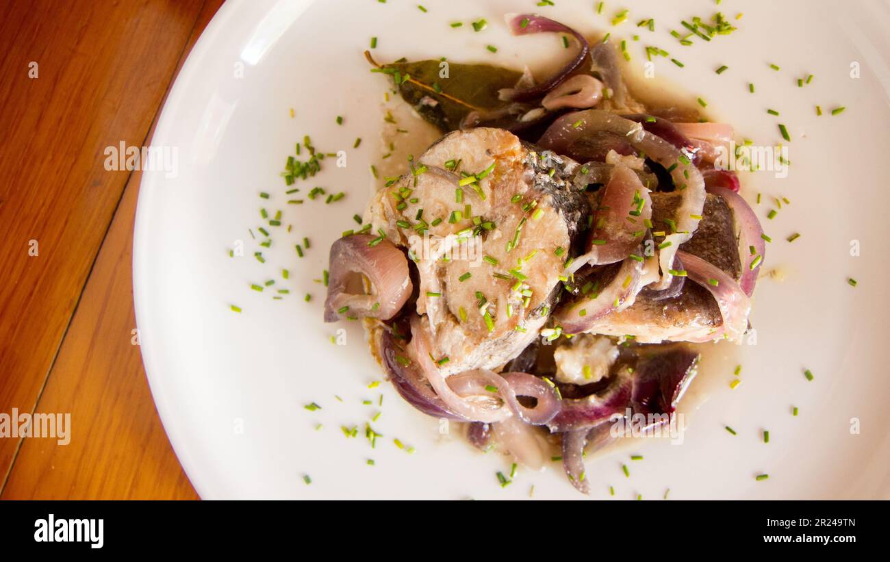 Hake fish cooked with red onion in a spanish restaurant Stock Photo - Alamy