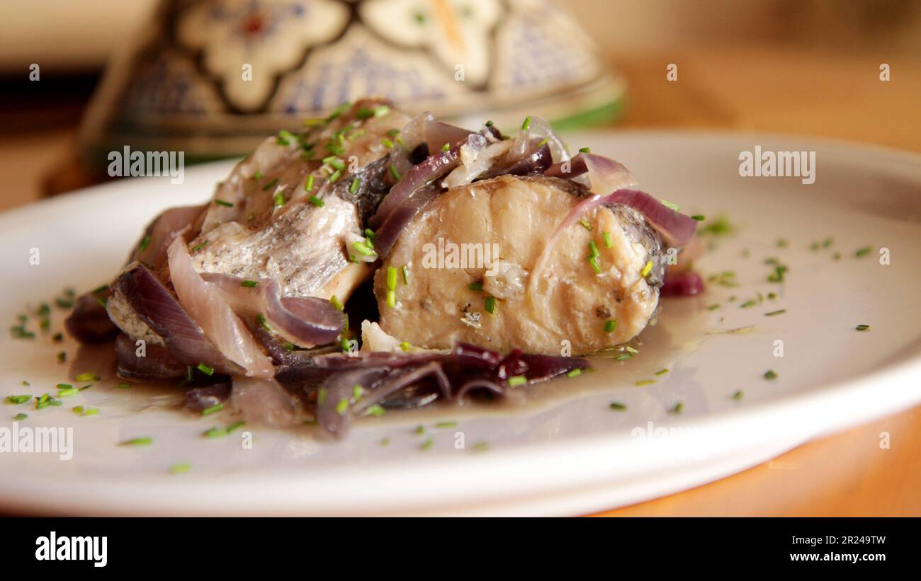 Hake fish cooked with red onion in a spanish restaurant Stock Photo - Alamy